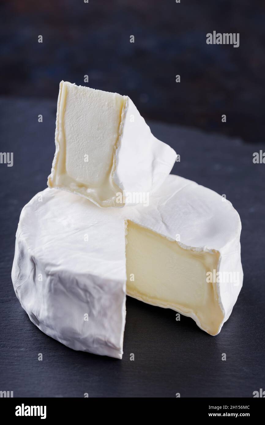 Camembert close-up on a dark background. Soft cheese with white mold on ...