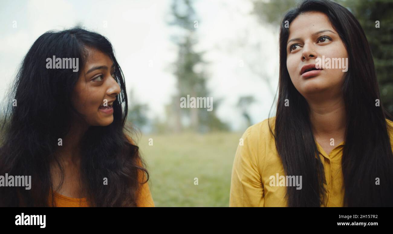 Of two young South Asian female friends talking at a picnic blanket in ...