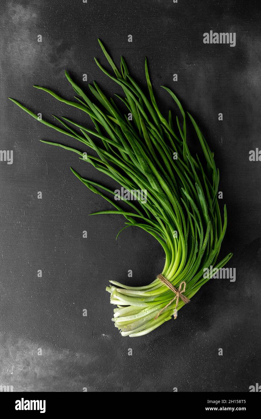 a bunch of green fresh onions or scallion on a dark background, top ...