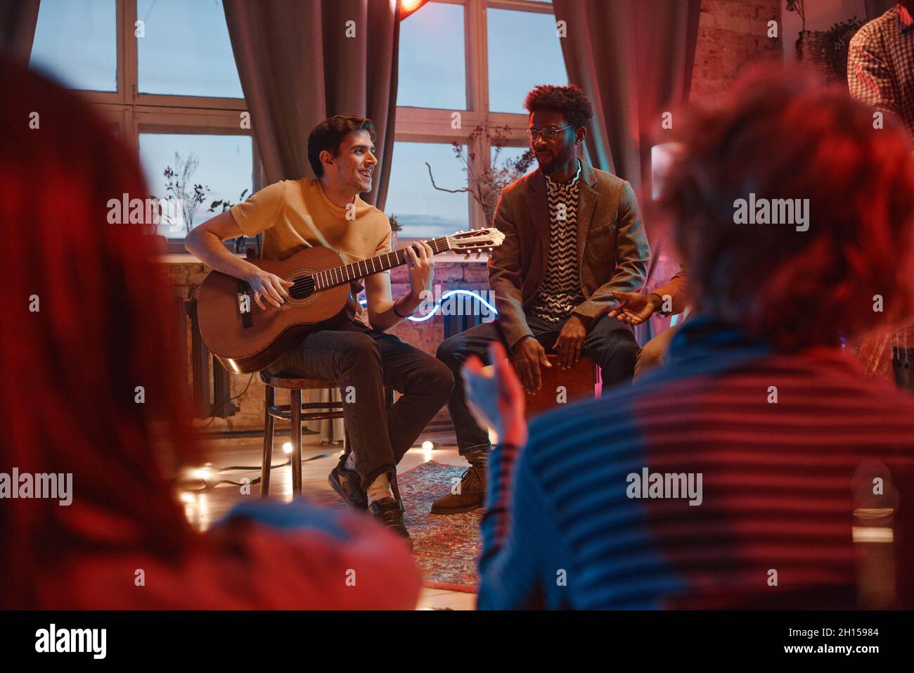Young man playing guitar with his friend who singing they performing ...