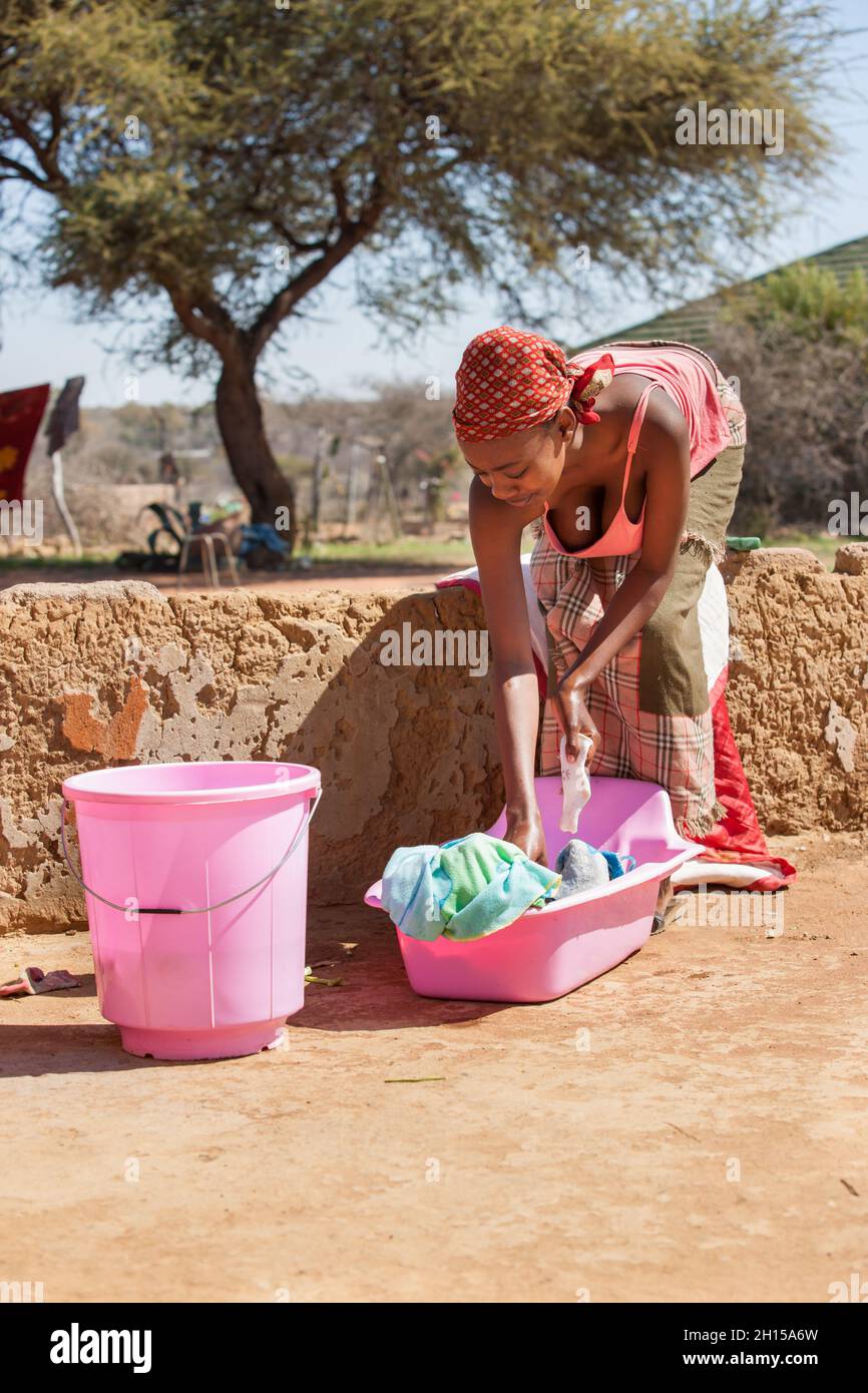 Single young African woman in a village in Botswana washing her clothes ...