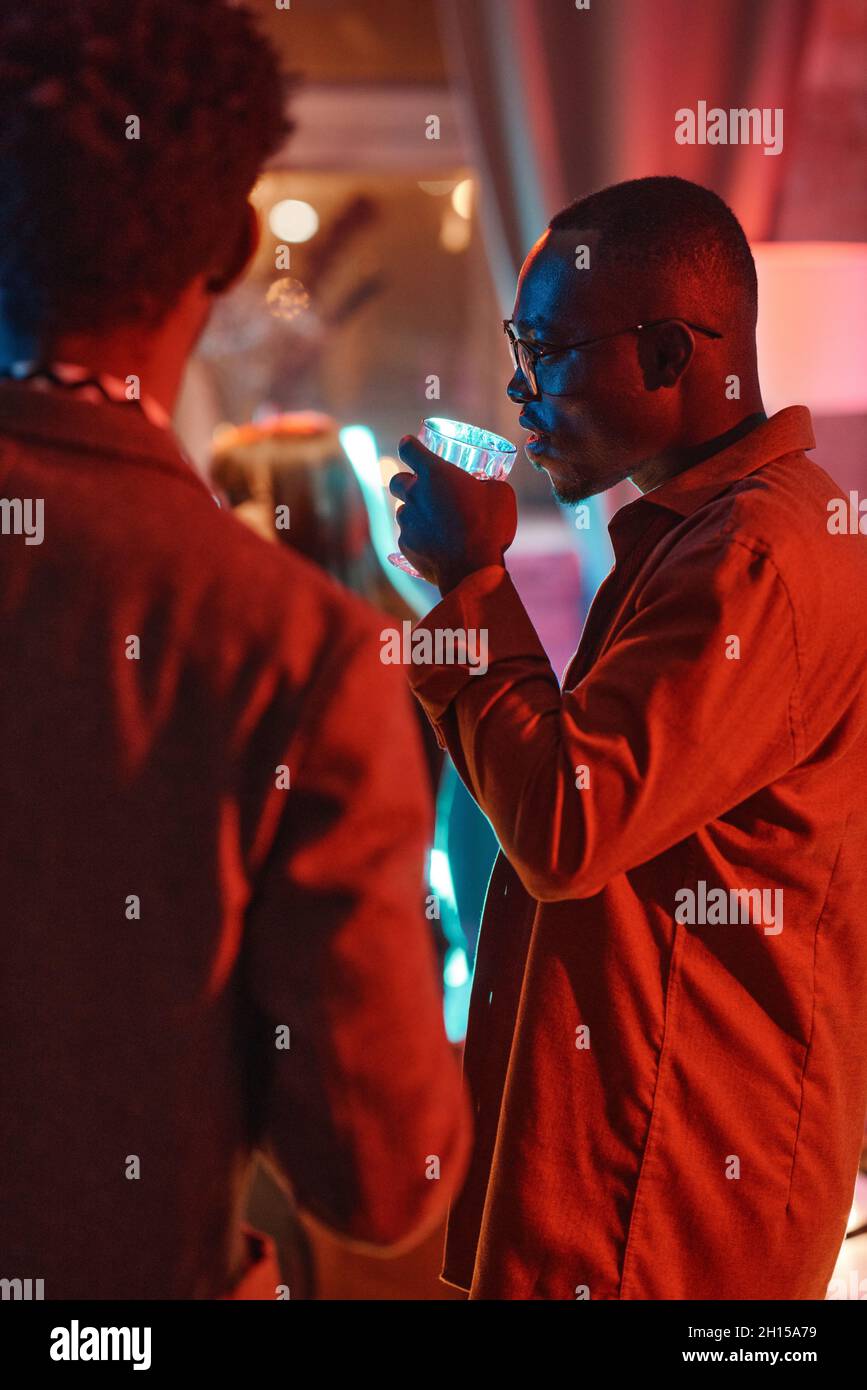 African young man drinking alcohol drinks at a party in night club ...