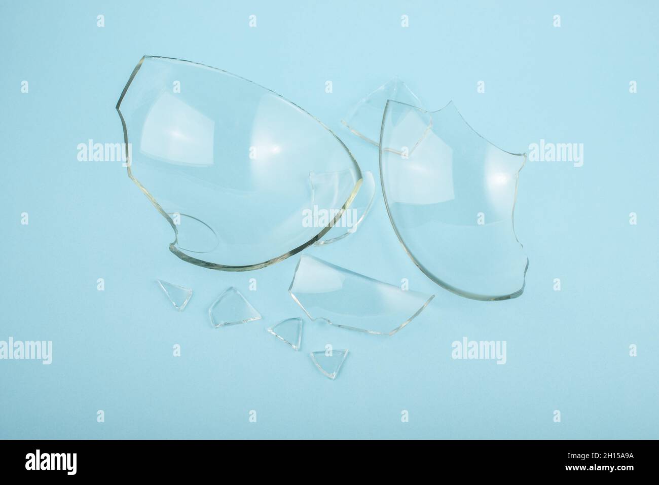 Broken glass pieces on pastel blue background. Close up, top view ...