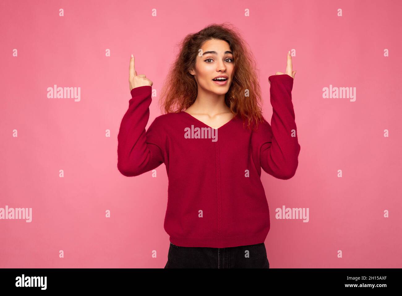 Photo of pretty astonished young woman pointing fingers up at copyspace ...