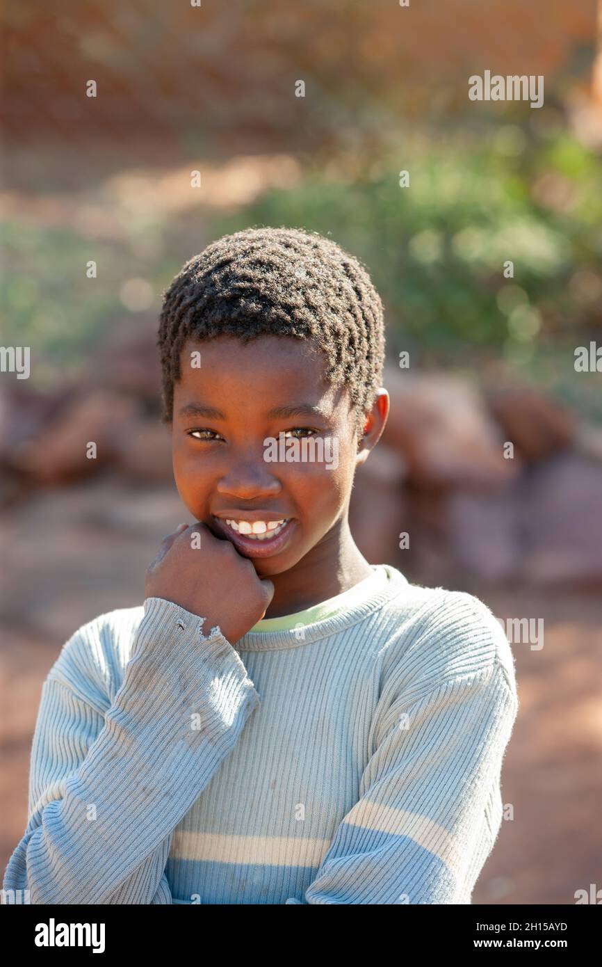 African child in a village in Botswana standing in front of the fence ...