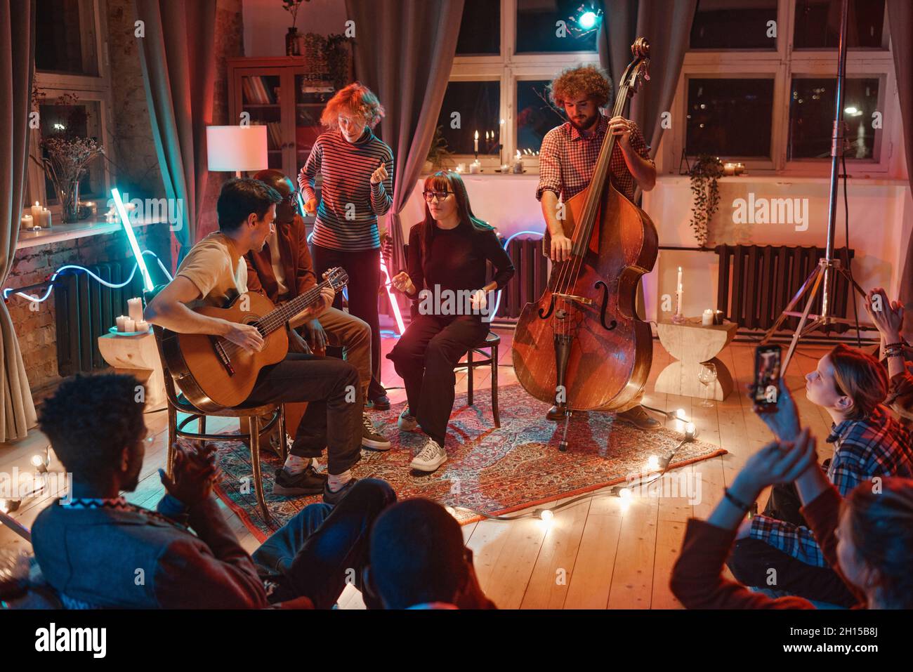 Young people playing musical instruments and singing while gathering ...