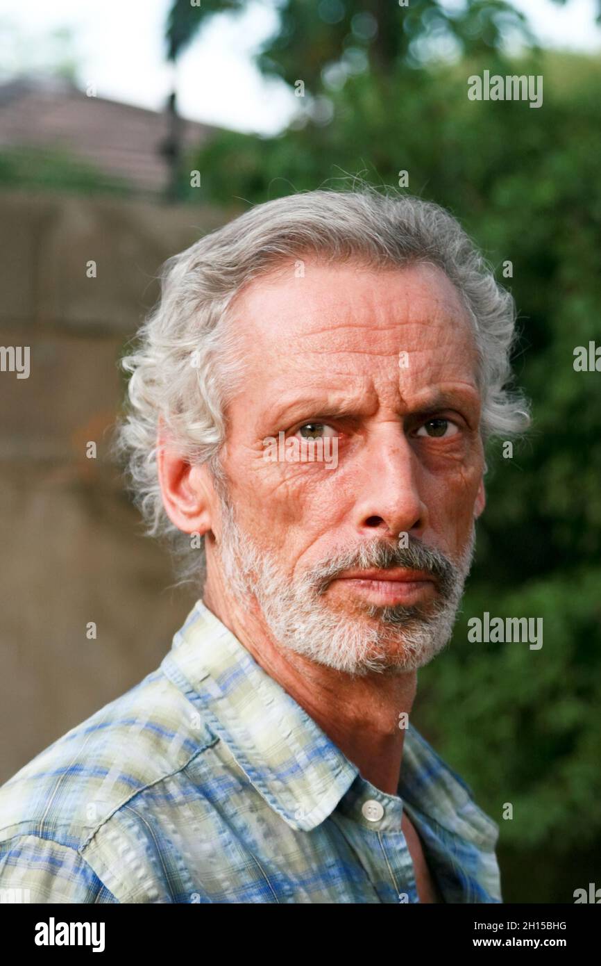 retired man walking in his garden in the yard of his house, lifestyle ...