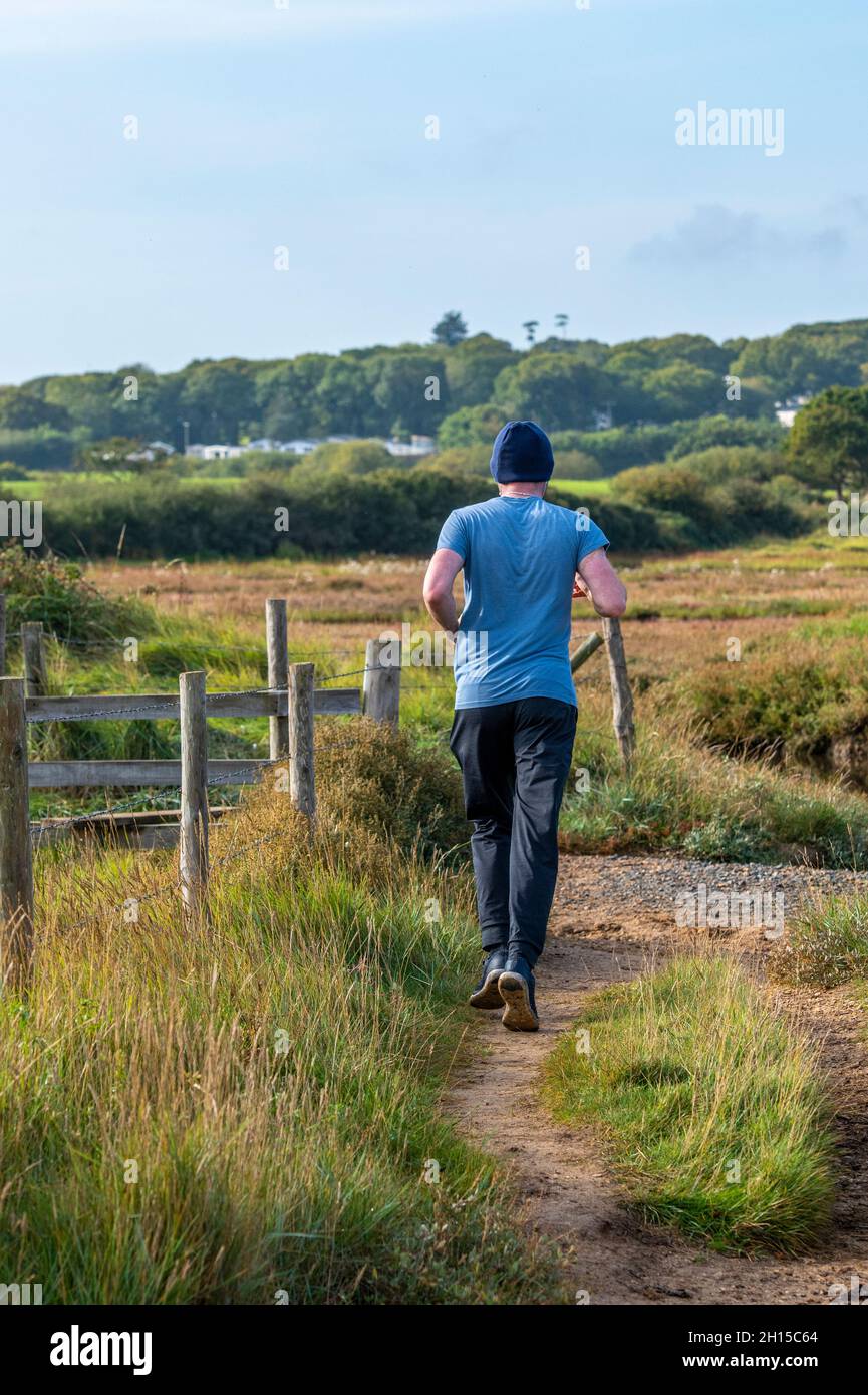 man running alone in the countryside along a grassy tack. keeping fit ...