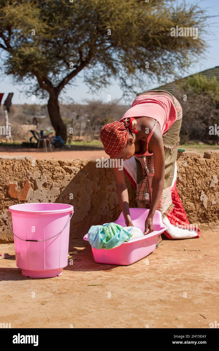 Single young African woman in a village in Botswana washing her clothes ...