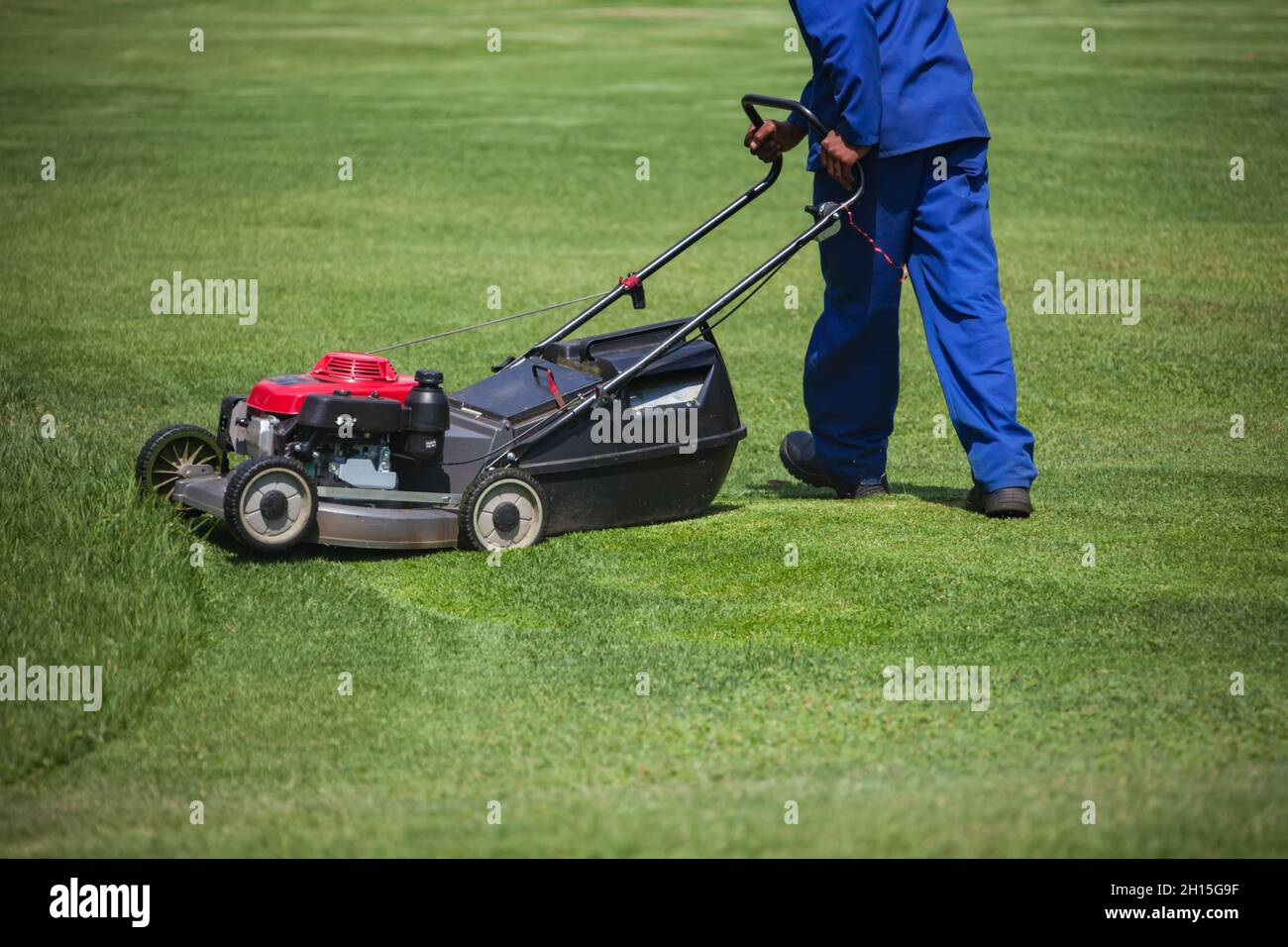 African man cutting grass with a lawnmower Stock Photo - Alamy