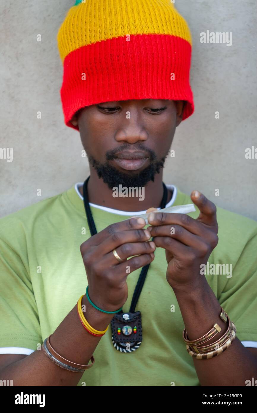 African rastafarian man preparing to roll a joint and smoke marihuana ...