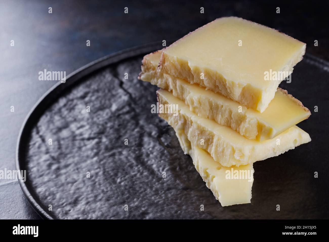 Hard cheese pieces on a dark background. Goat cheese on a slate board ...