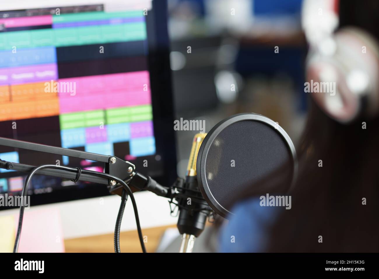 Woman in headphones in front of microphone looks at monitor with sound ...
