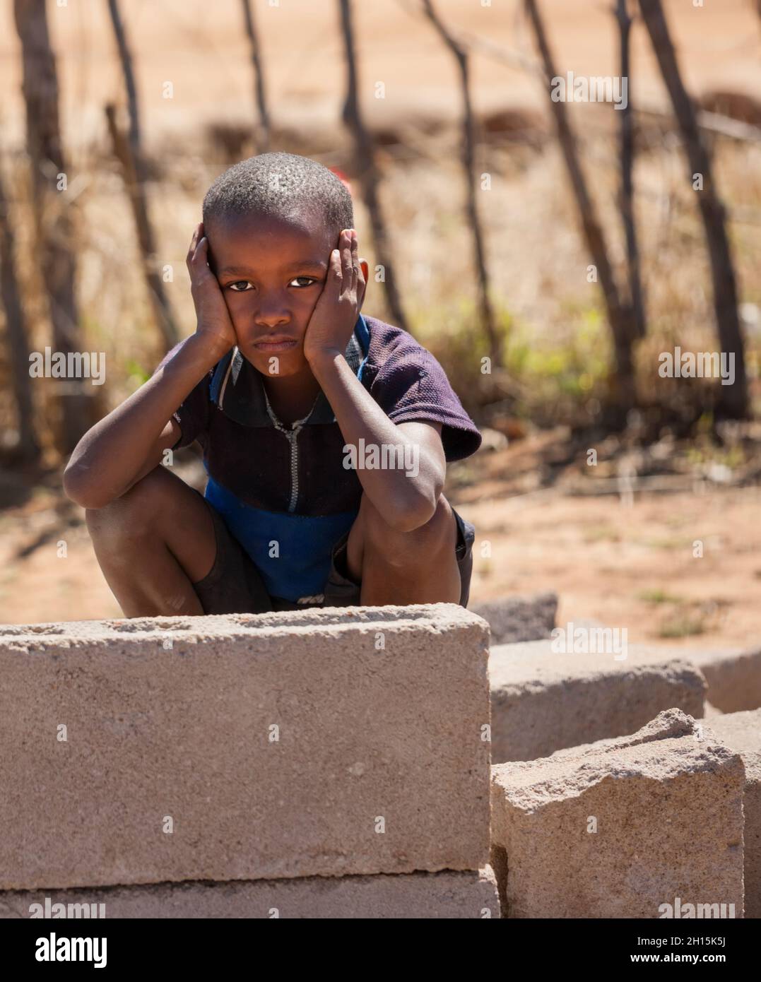 Single African child in a village in Botswana waiting in the yard, sad ...