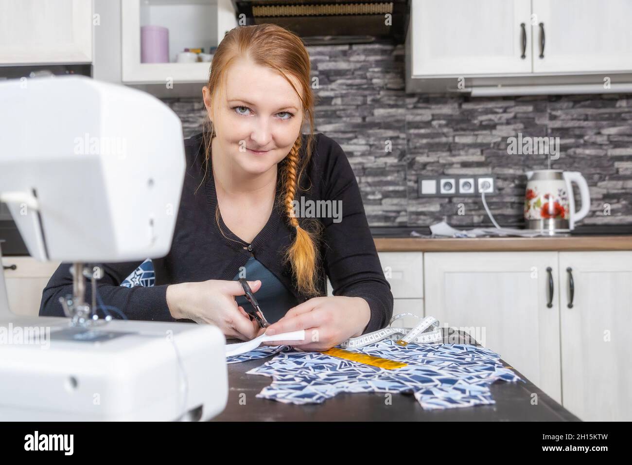 Home sewing concept. Young woman iis cutting fabric looking at the ...