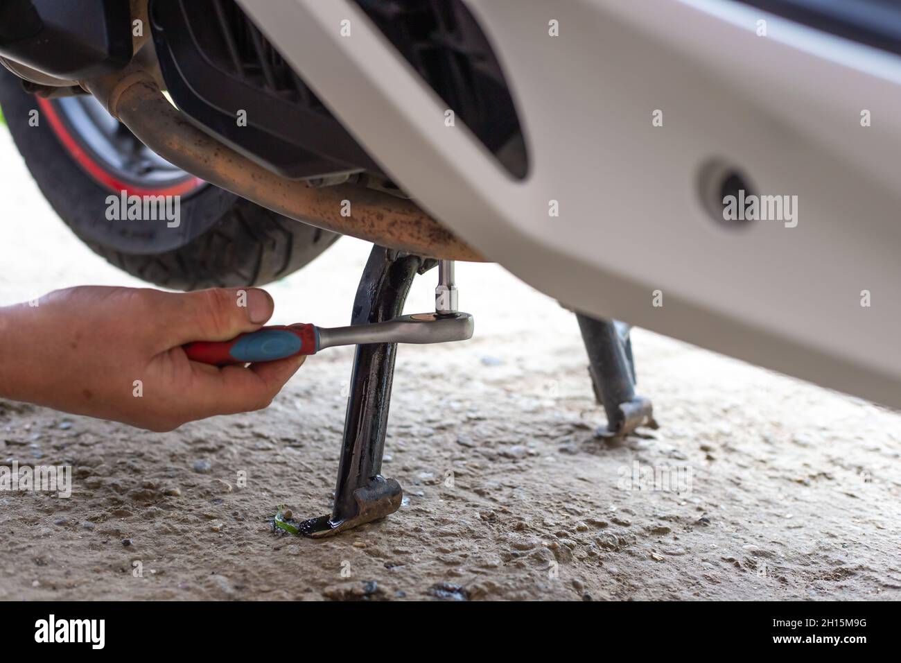 Unscrewing the drain plug of the motorbike engine crankcase to drain ...