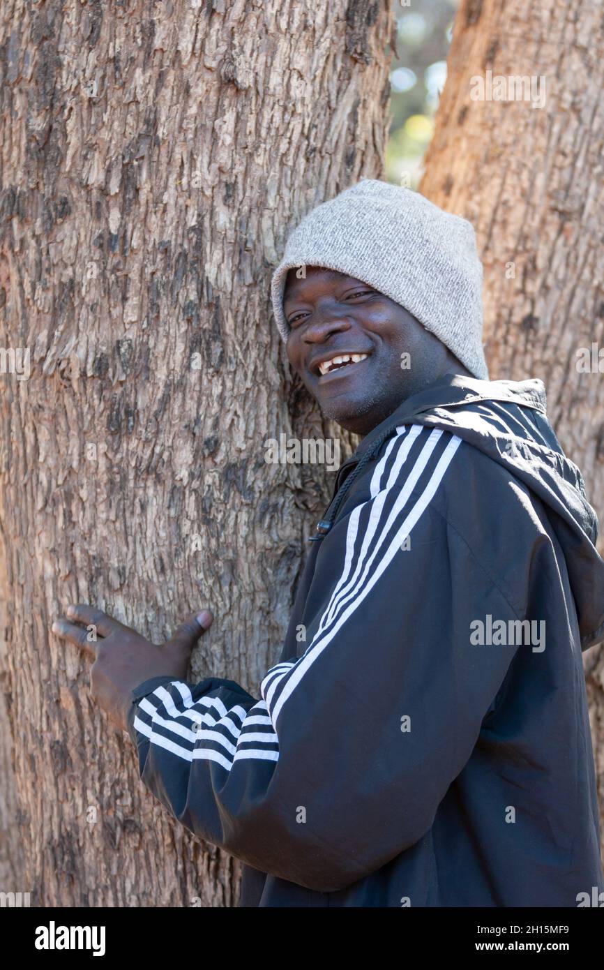 Young African man hugging a tree in Botswana Africa Stock Photo - Alamy