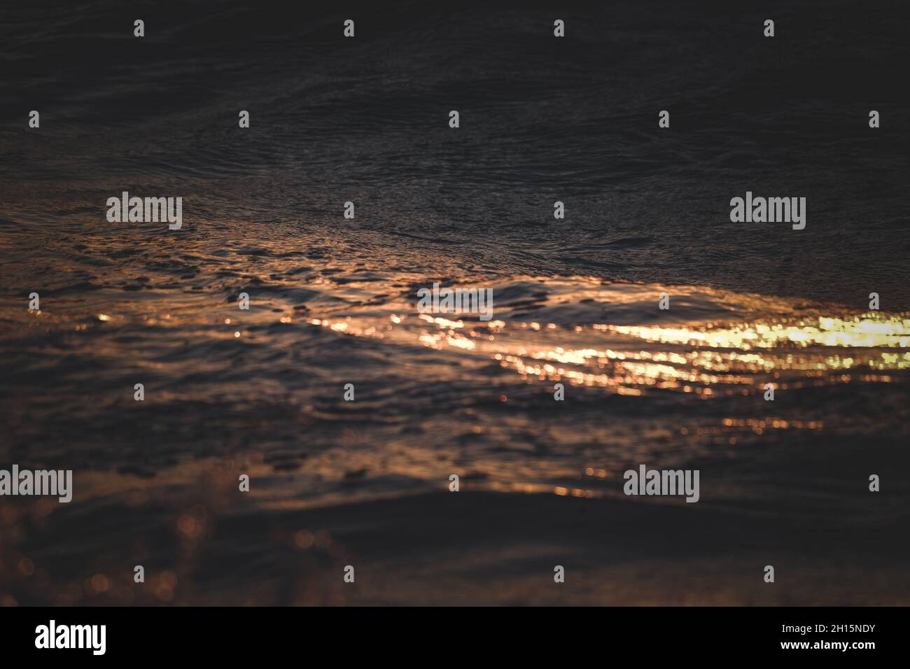 Serene scenery of the ripples of the ocean in sunbeams at golden sunset ...