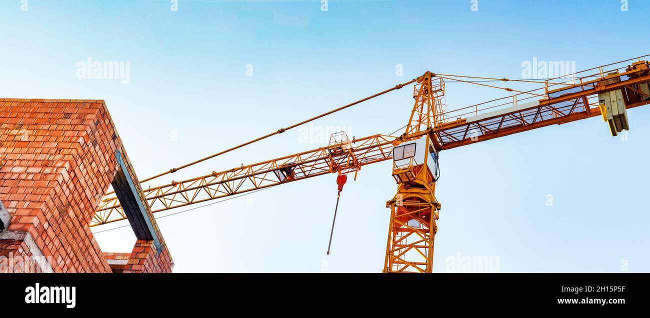 Photo of orange colored building crane on blue sky background and ...