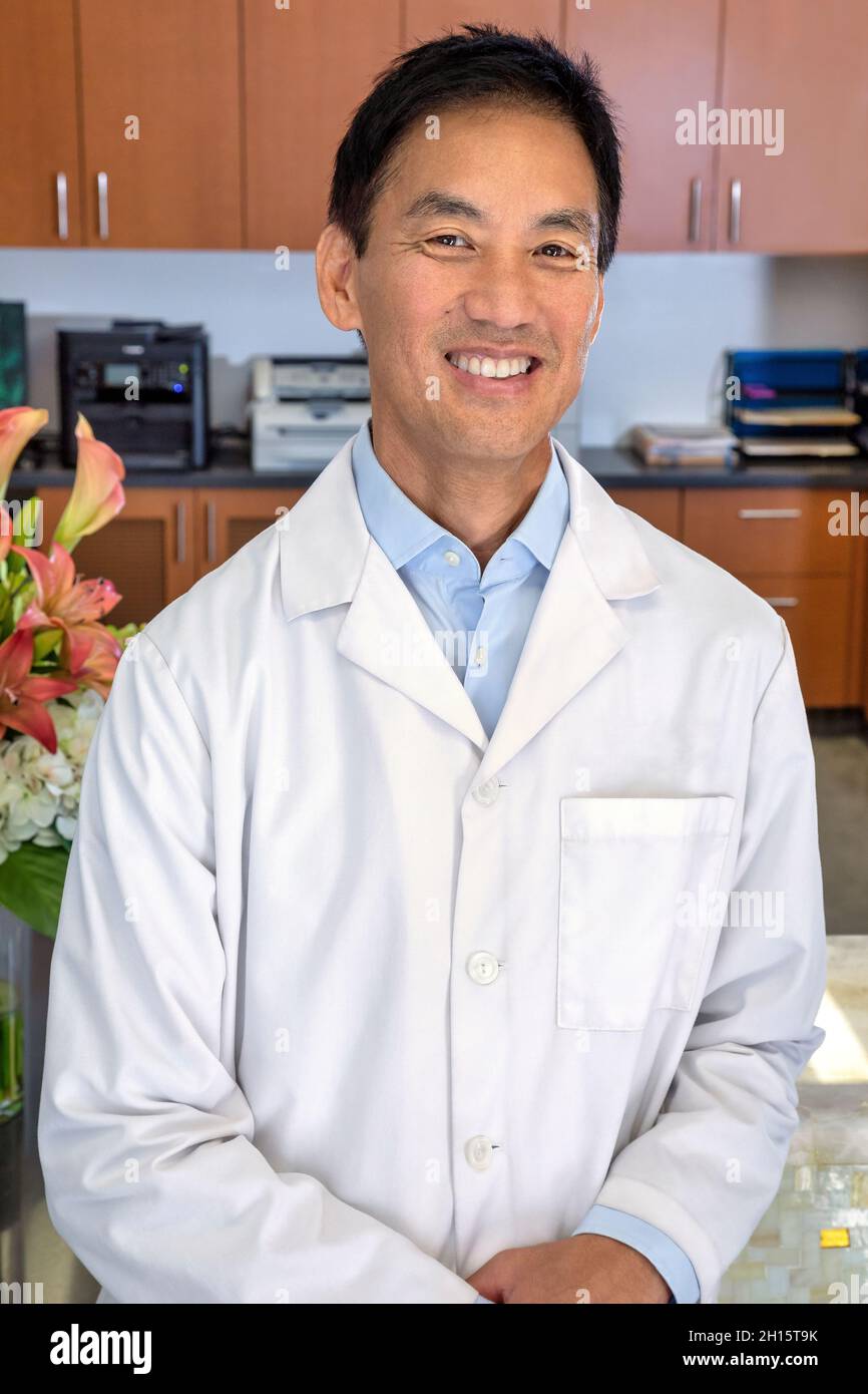 Asian male doctor standing inside his office Stock Photo - Alamy