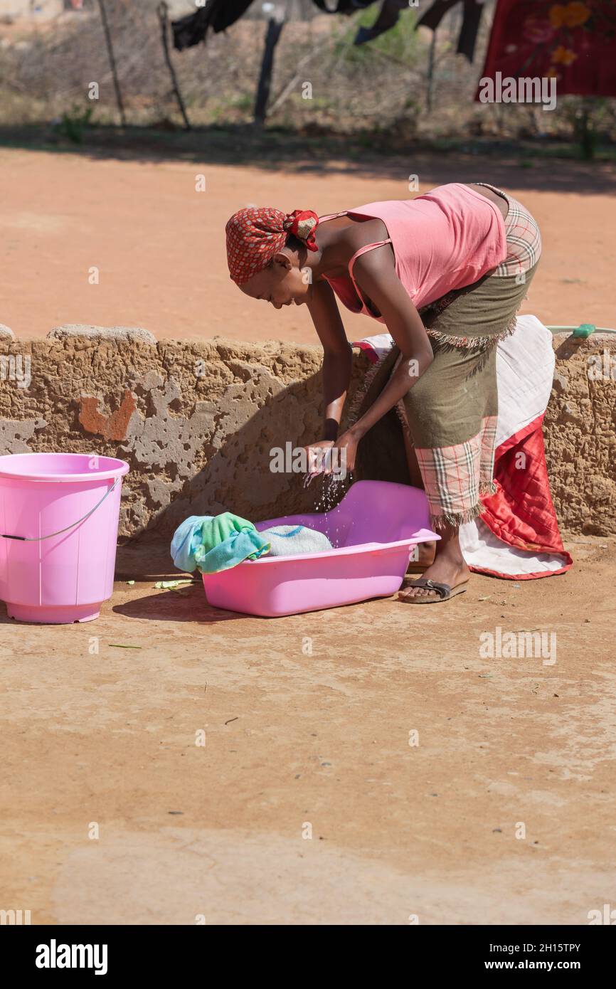 Single young African woman in a village in Botswana washing her clothes ...