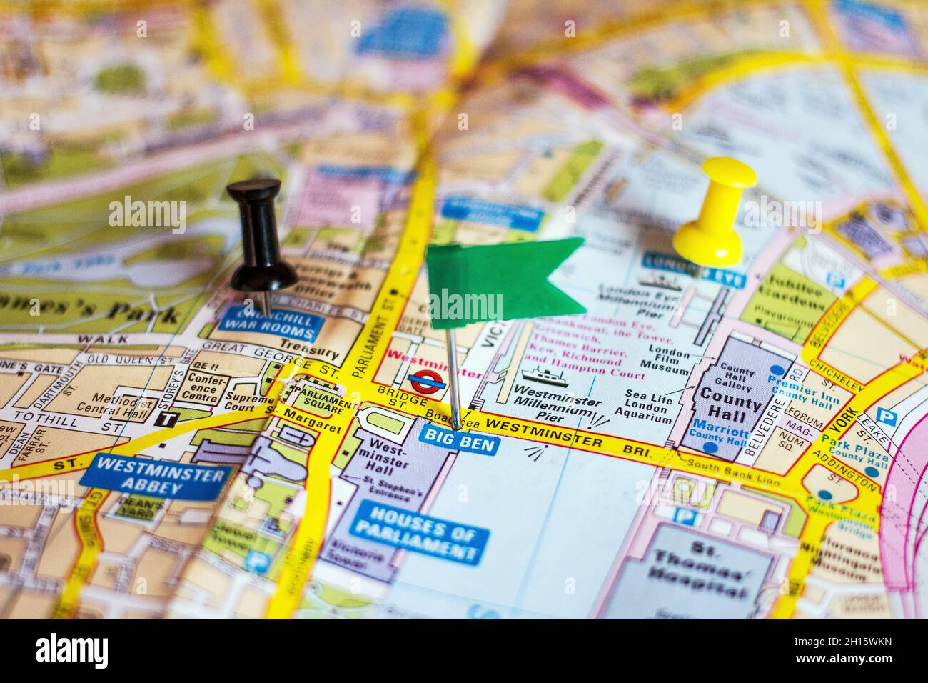 Closeup of pushpins and a small flag on a map of London with a blurry ...