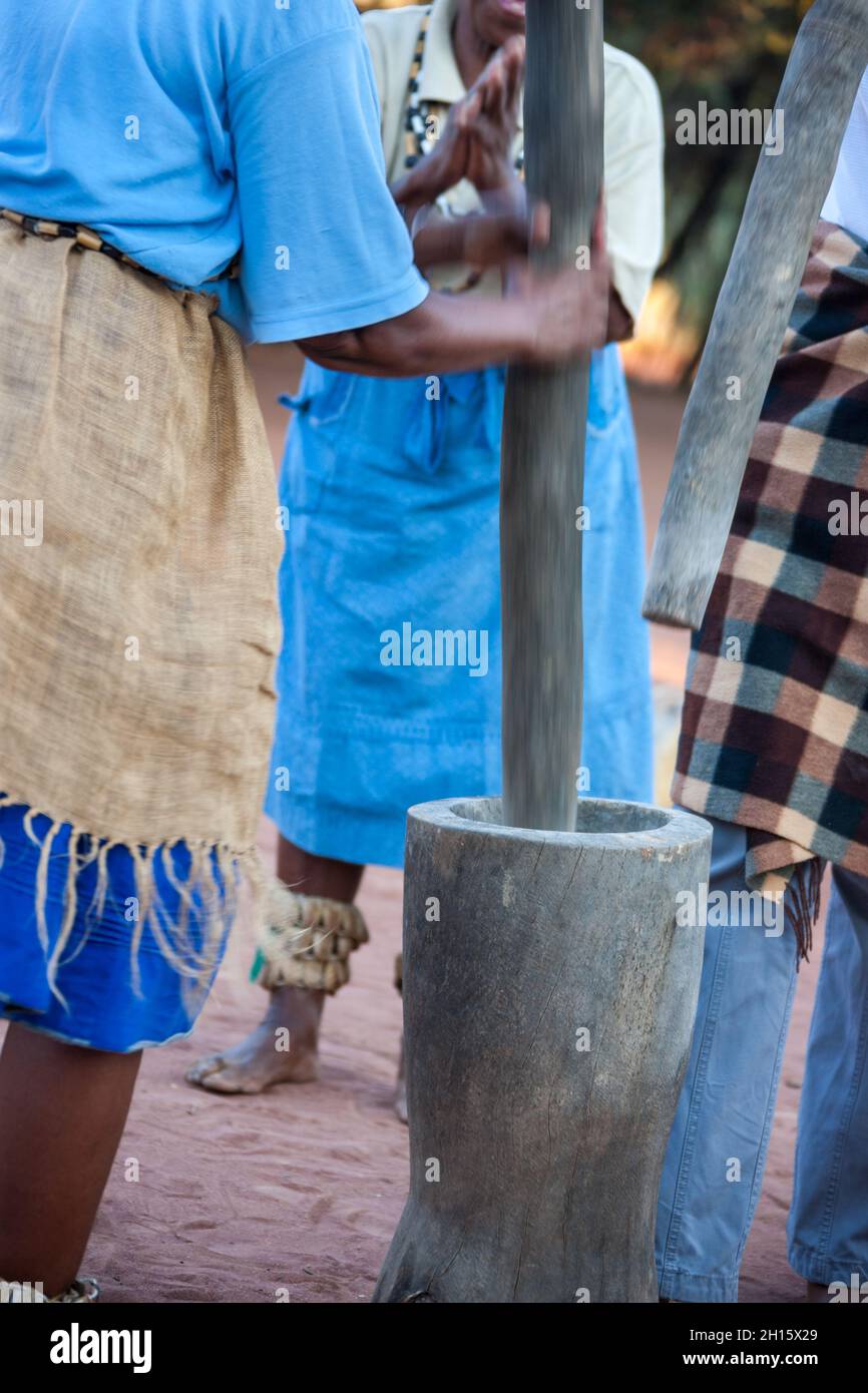 Old African woman grinding sorghum and corn in a traditional way, in ...