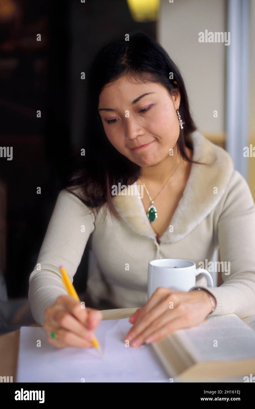 Chinese woman student studies in coffee shop MR - Model Released Stock ...