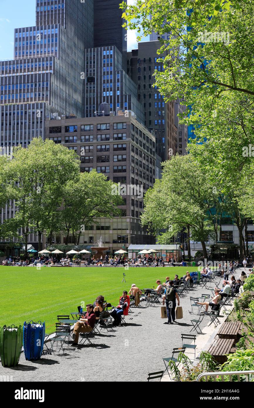 Visitors relaxing by the lawn in Bryant Park with skyscrapers of ...