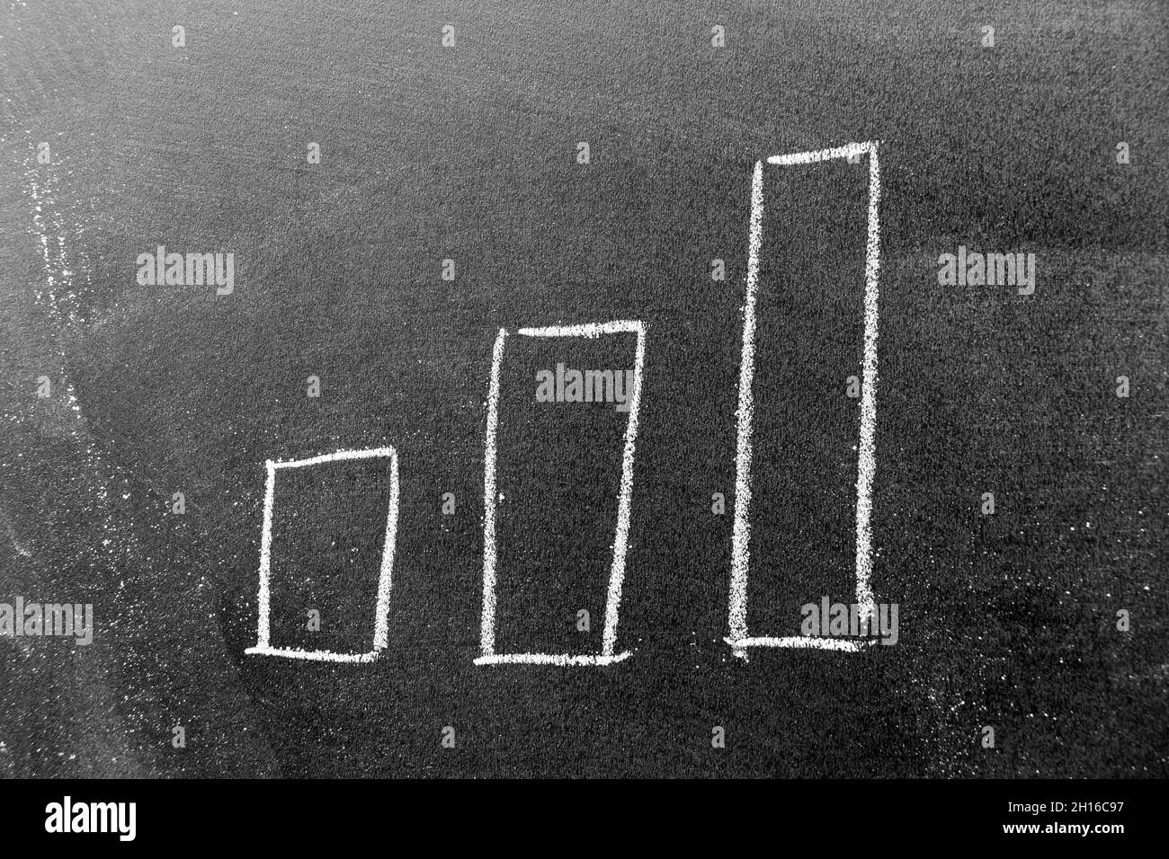 White color chalk hand drawing in uptrend barchart shape on black board ...