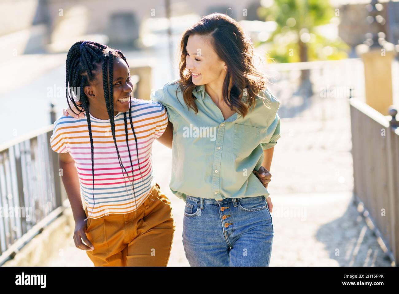 Two friends talking together on the street. Multiethnic women Stock ...