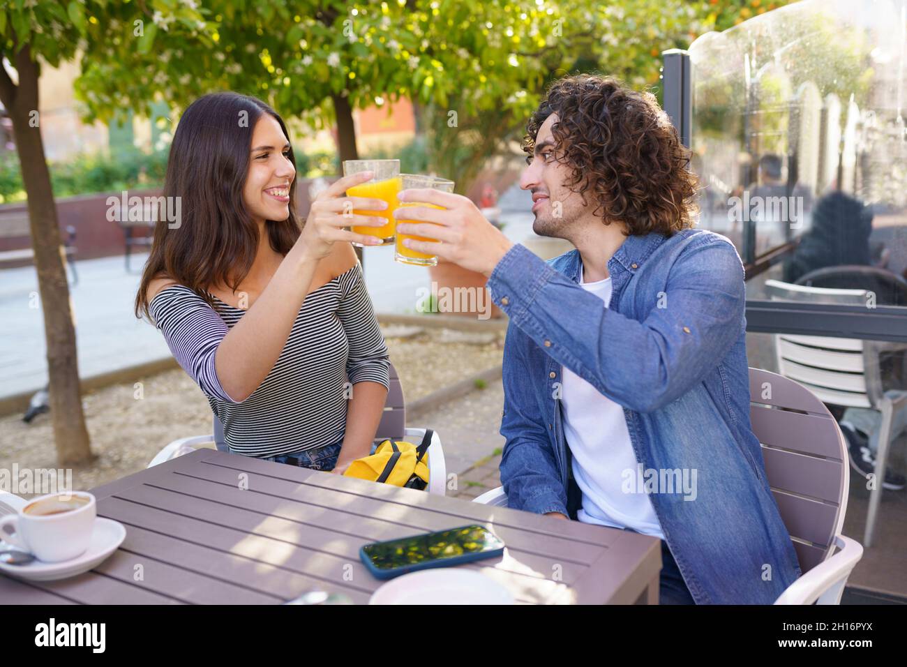 Couple of friends toasting while having a drink with their multi-ethnic ...