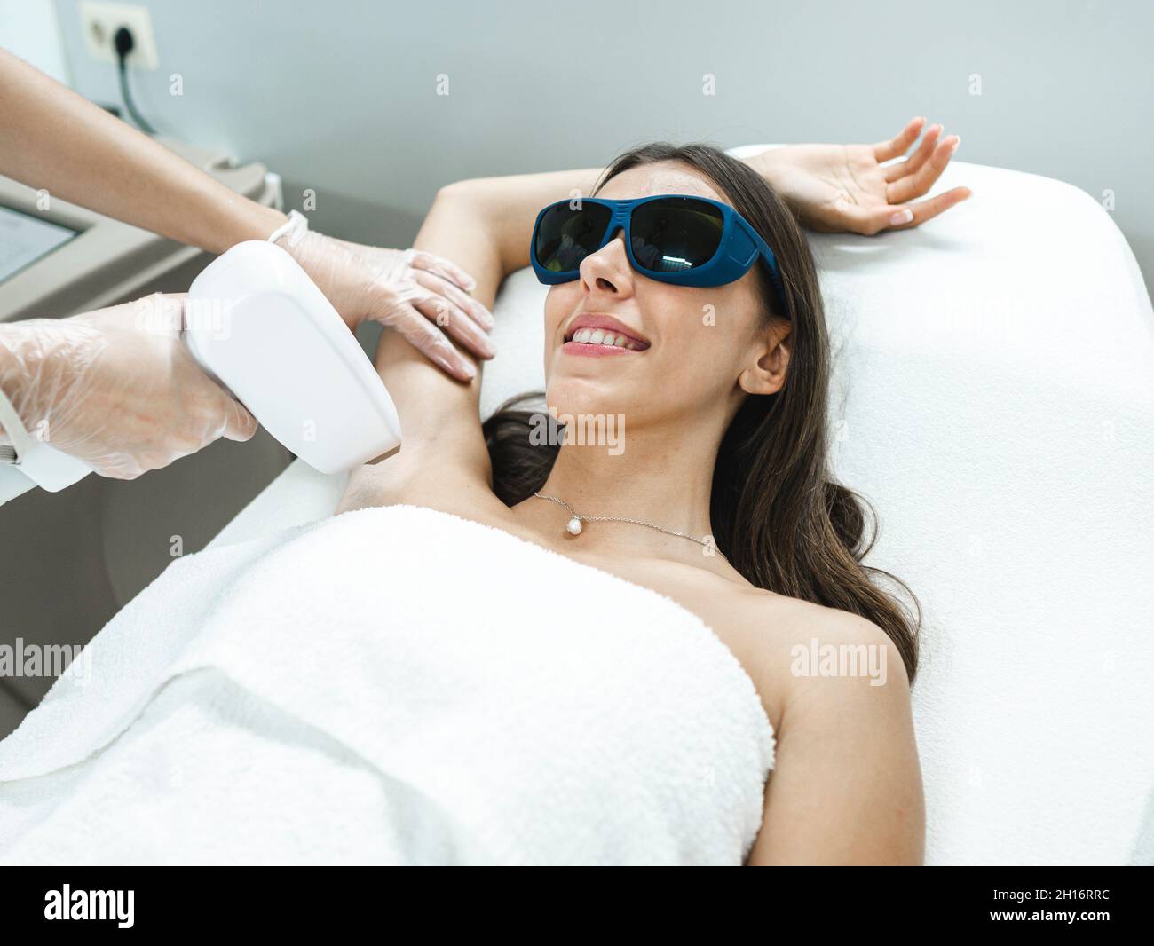 From above young master in goggles doing laser hair removal procedure ...