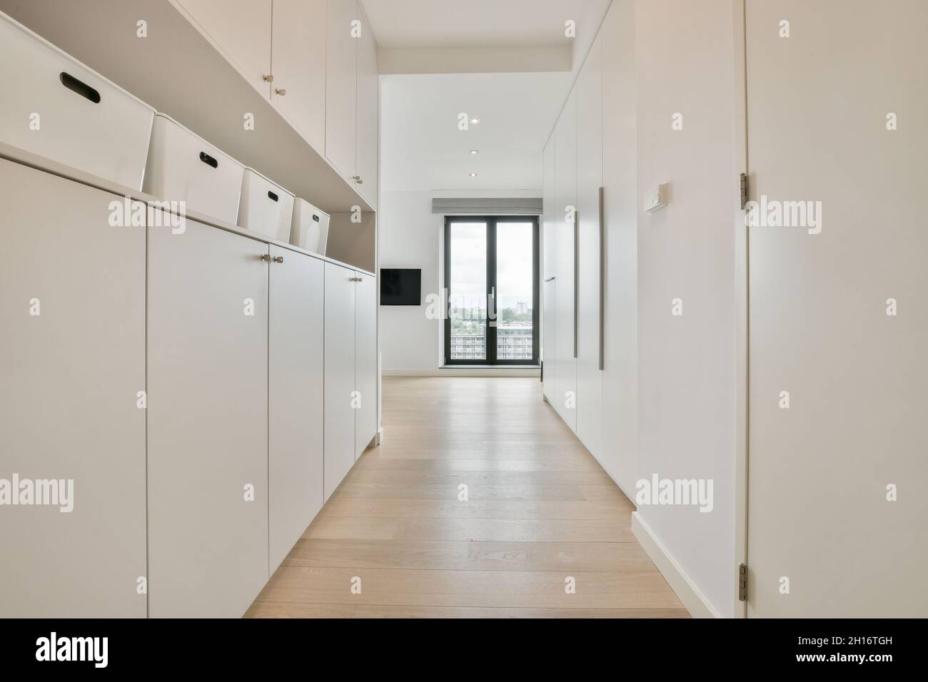 Long corridor between closed door and various white cupboards with ...