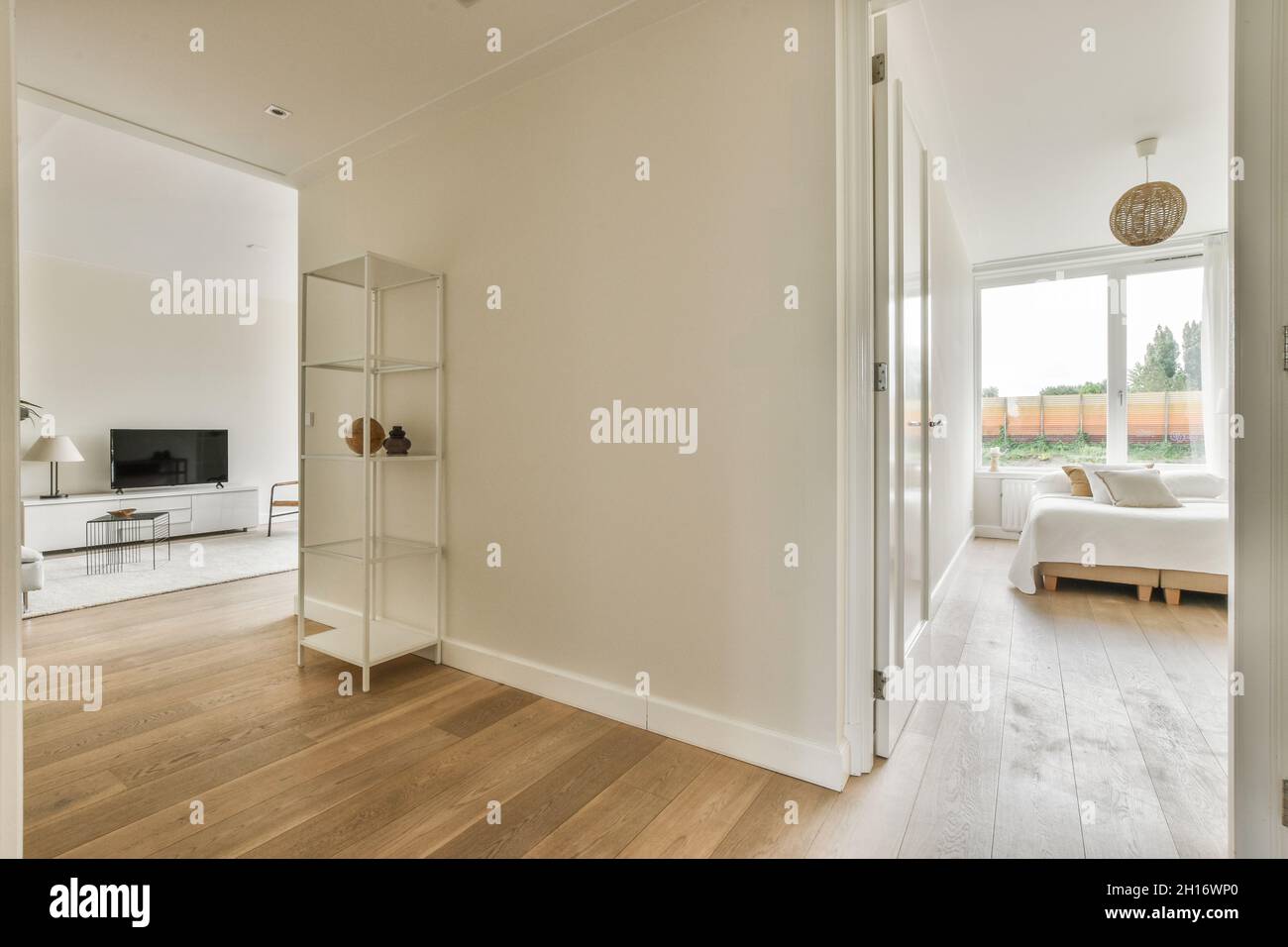 Light corridor with doors leading to living room with TV and bedroom ...