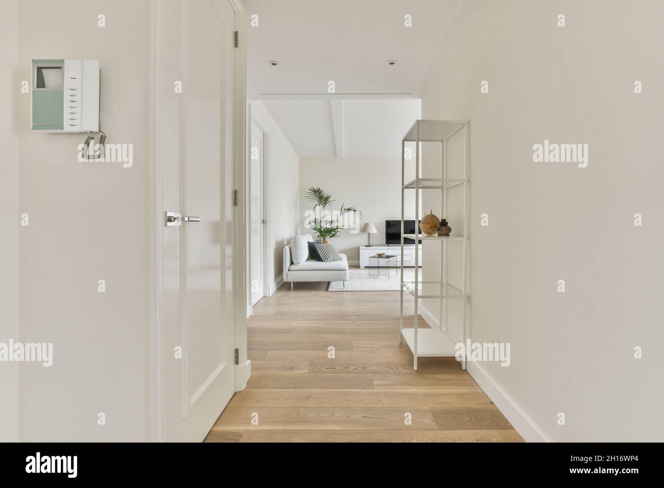 Light corridor with shelves leading to living room with couch in ...