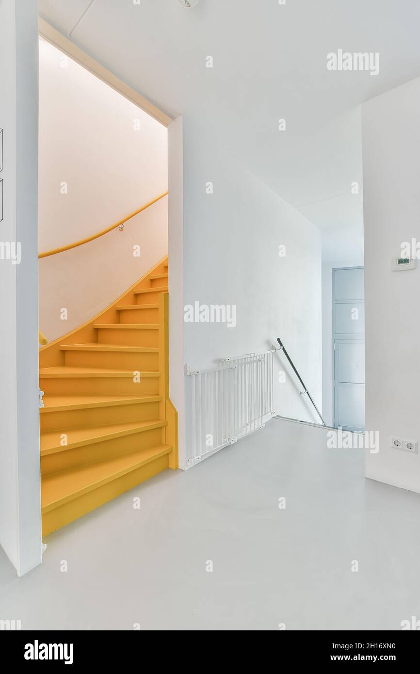 Wavy empty staircase against hall with fence and white walls in ...
