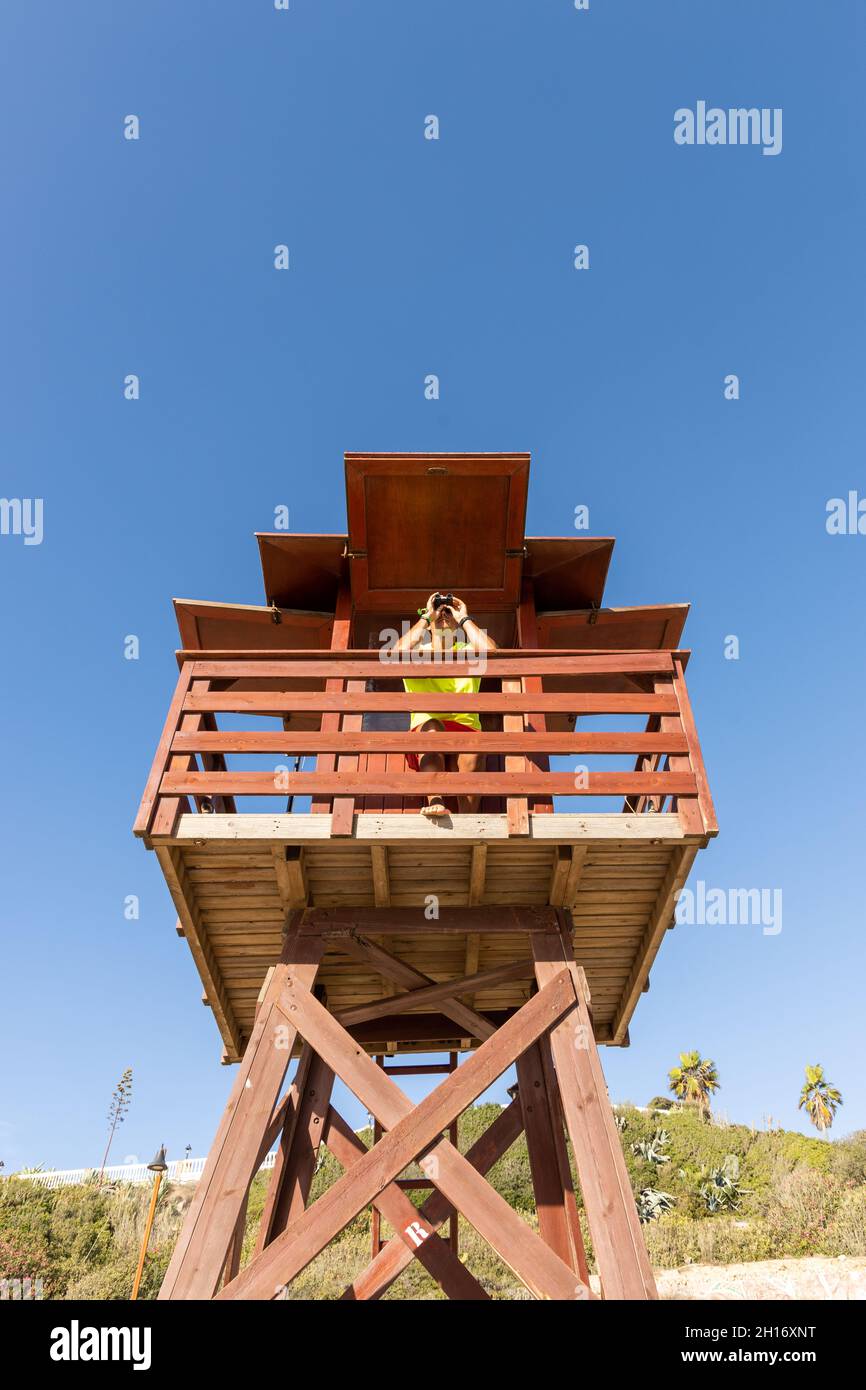 Low angle of looking through binoculars on wooden watchtower while ...