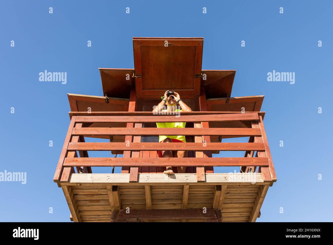 Low angle of looking through binoculars on wooden watchtower while ...