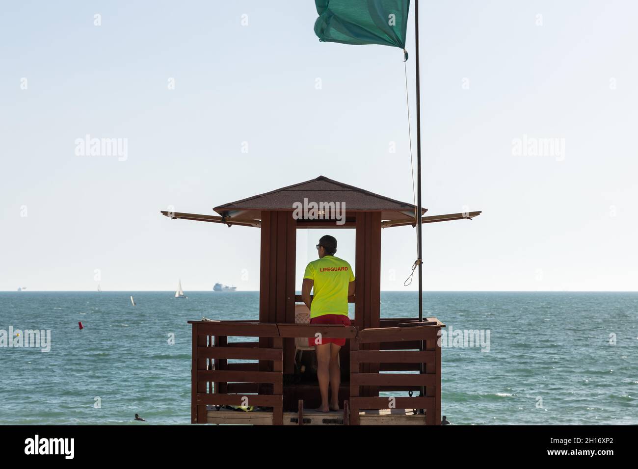 Full body back view of unrecognizable male lifeguard controlling safety ...