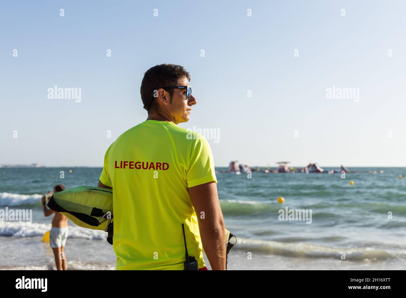 Back view of male lifeguard in shorts and t shirt and maintaining ...