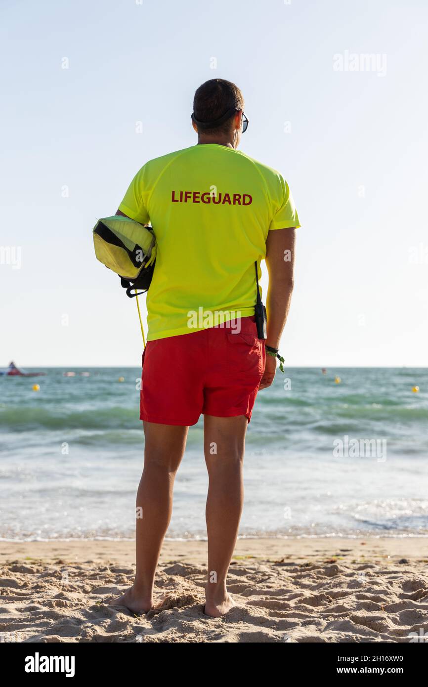 Full body back view of anonymous male lifeguard in shorts and t shirt ...