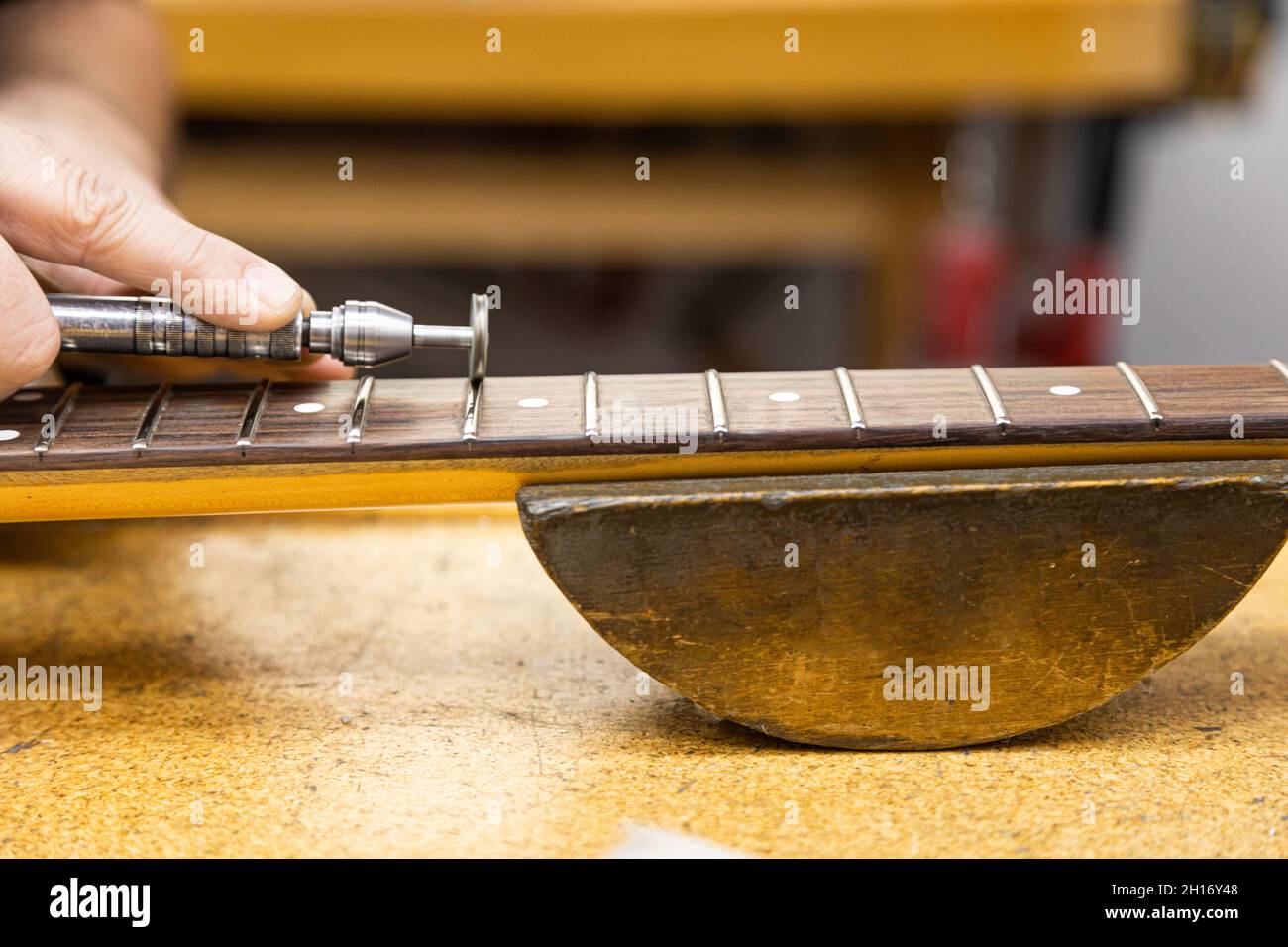 Crop anonymous master polishing frets on guitar neck with professional ...