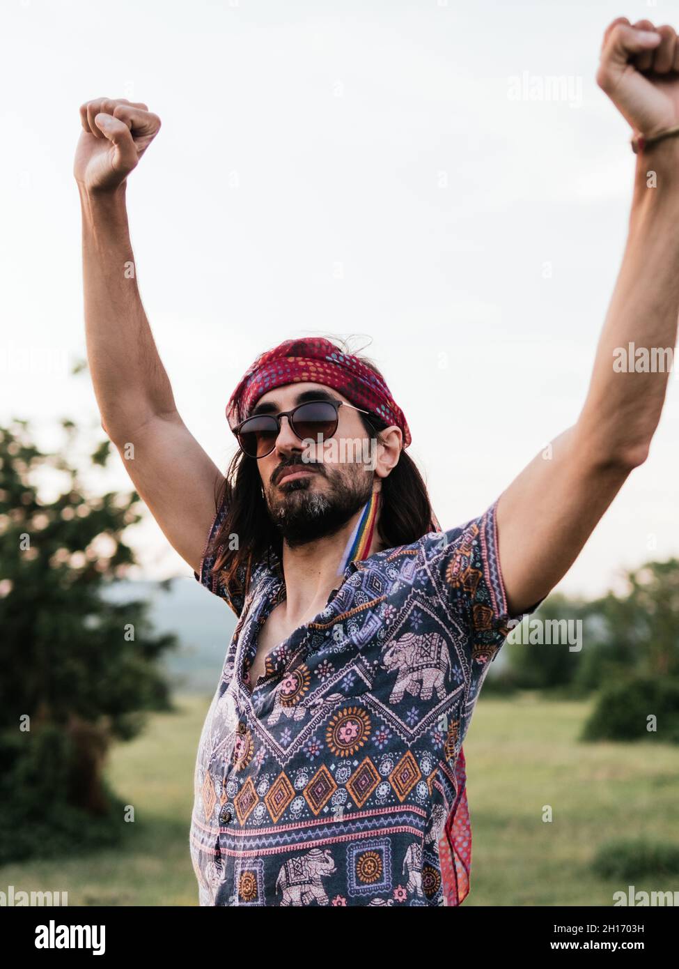 Emotionless man with hands raised and lgtbi flag painted on his neck ...