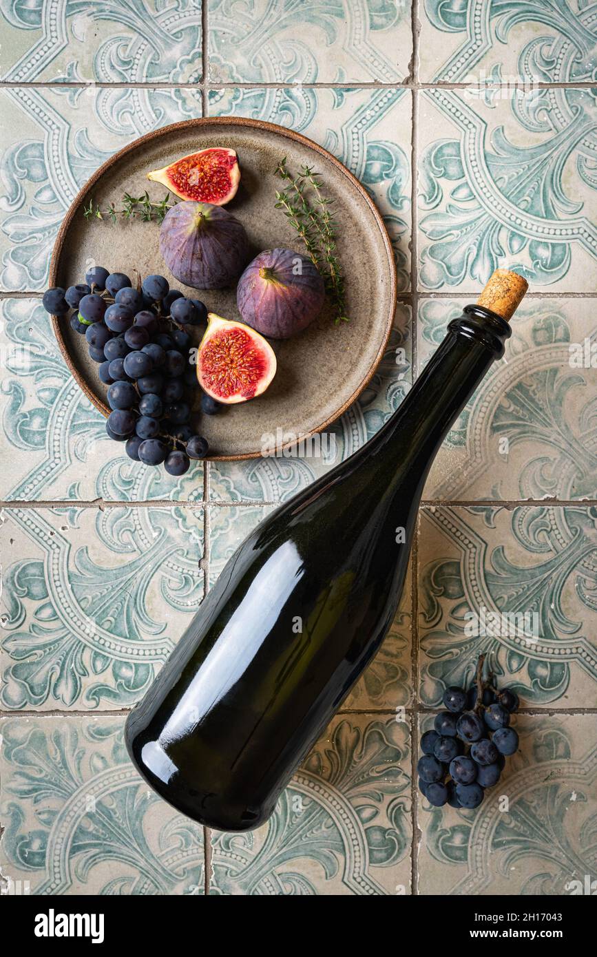 Wine bottle, grapes and figs on tile background top view with copy ...