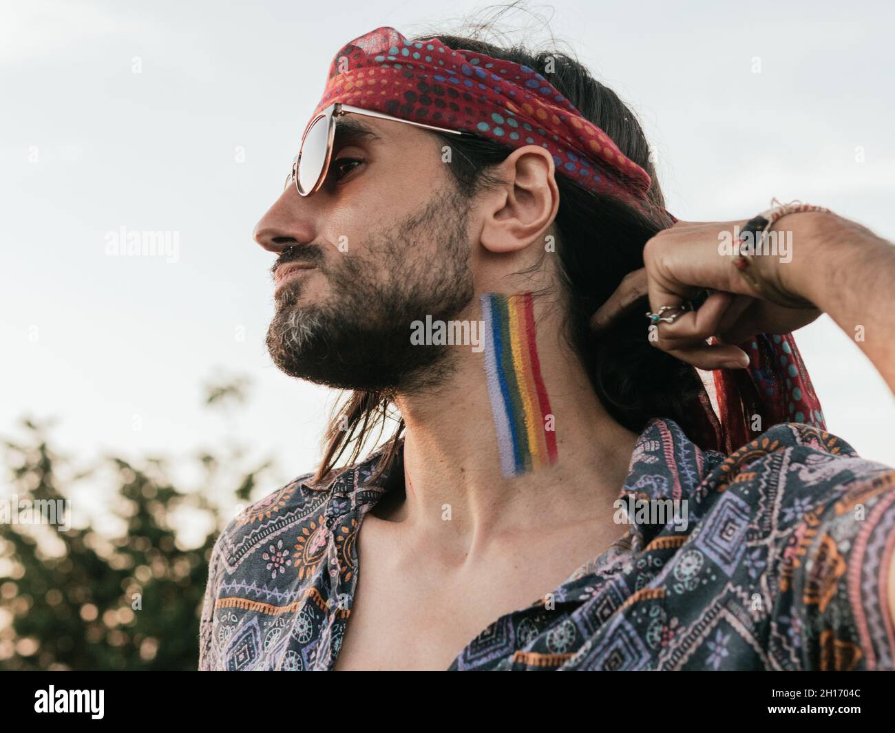 Side view of a emotionless man with lgtbi flag painted on his neck ...