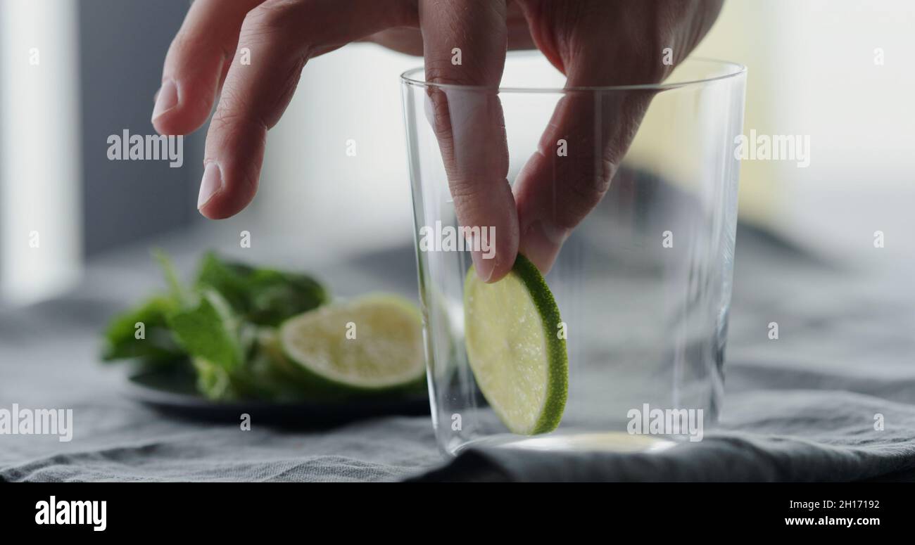 man put lime slices in tumbler glass on linen cloth, wide photo Stock ...