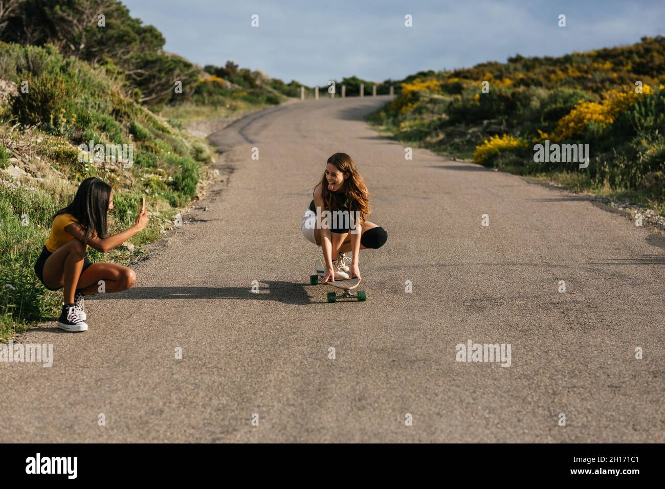 Full body of ethnic female sitting on haunches and taking picture on ...