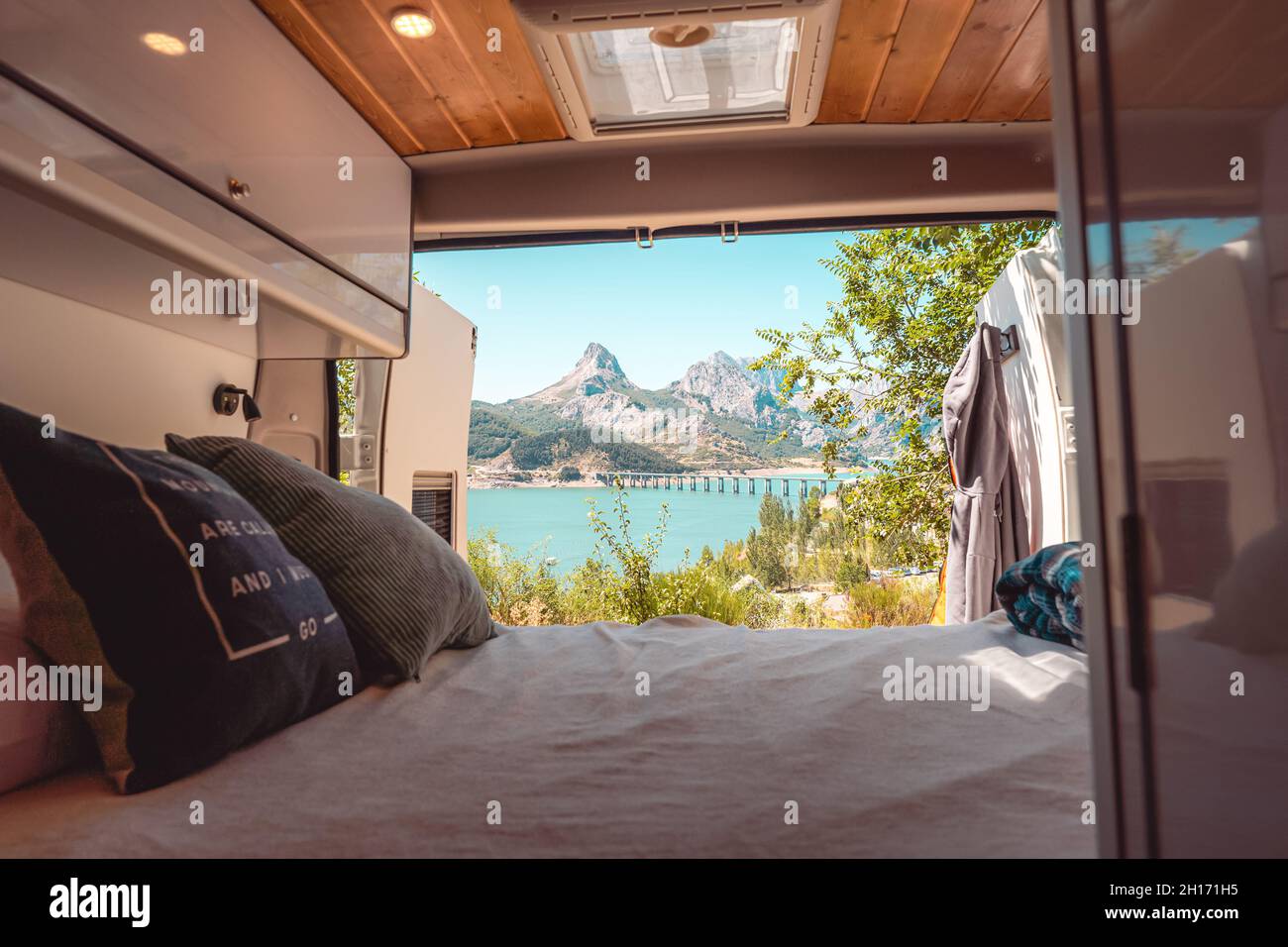 Comfortable bed with cushions and blanket in cozy traveling caravan ...