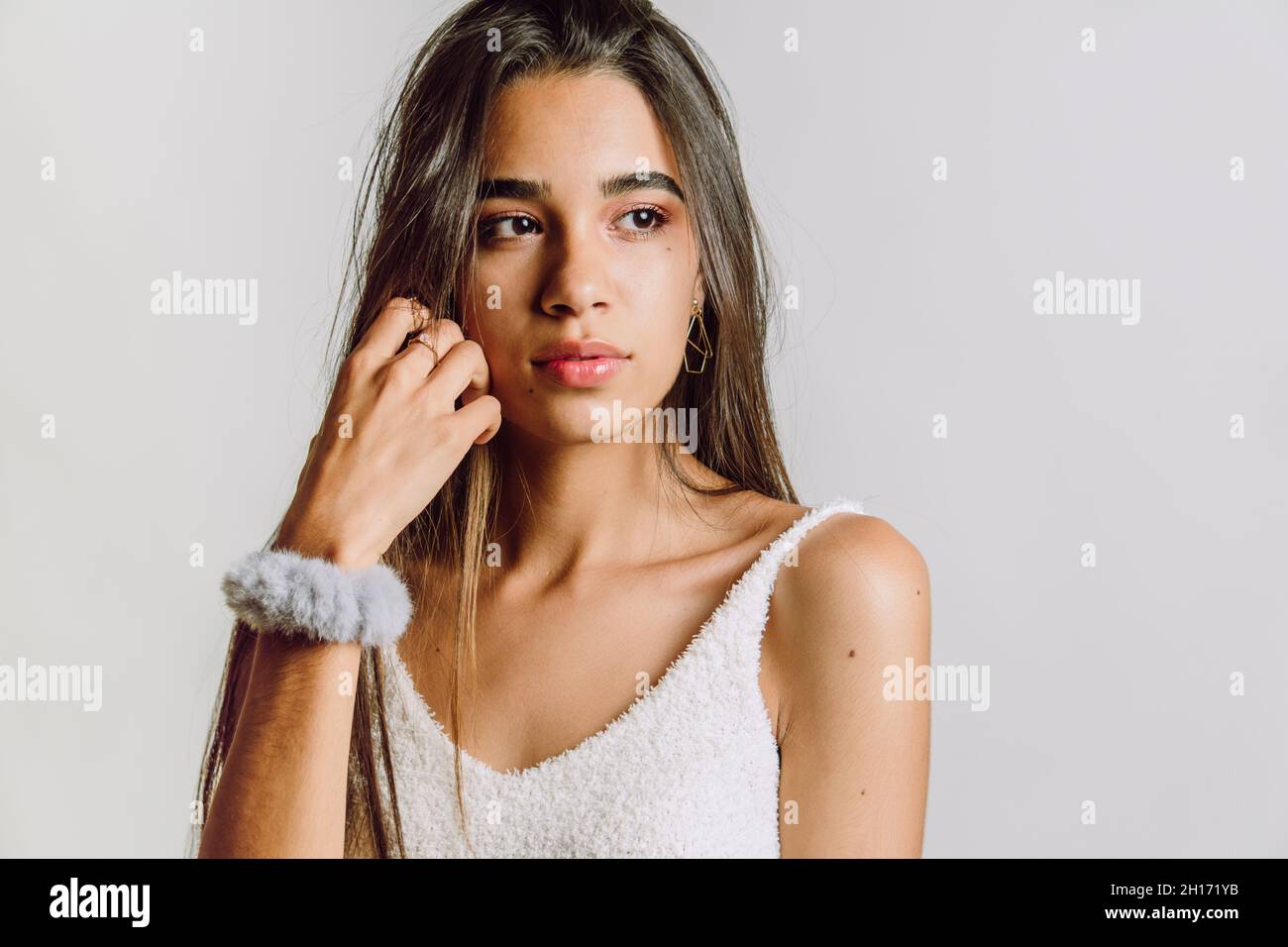 Reflective young Hispanic Woman with makeup looking away on light ...